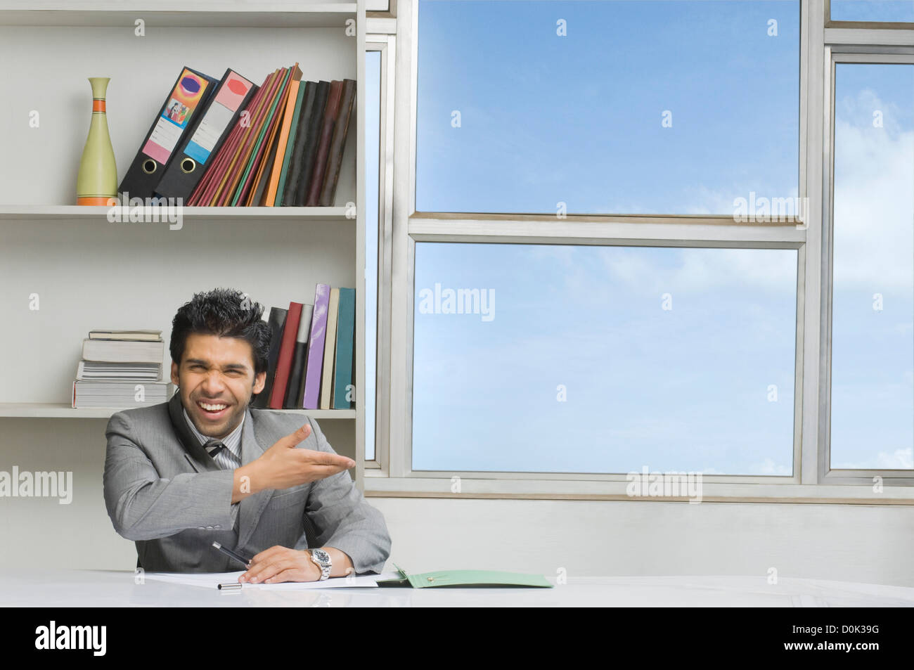 Businessman gesturing and smiling in an office Stock Photo - Alamy