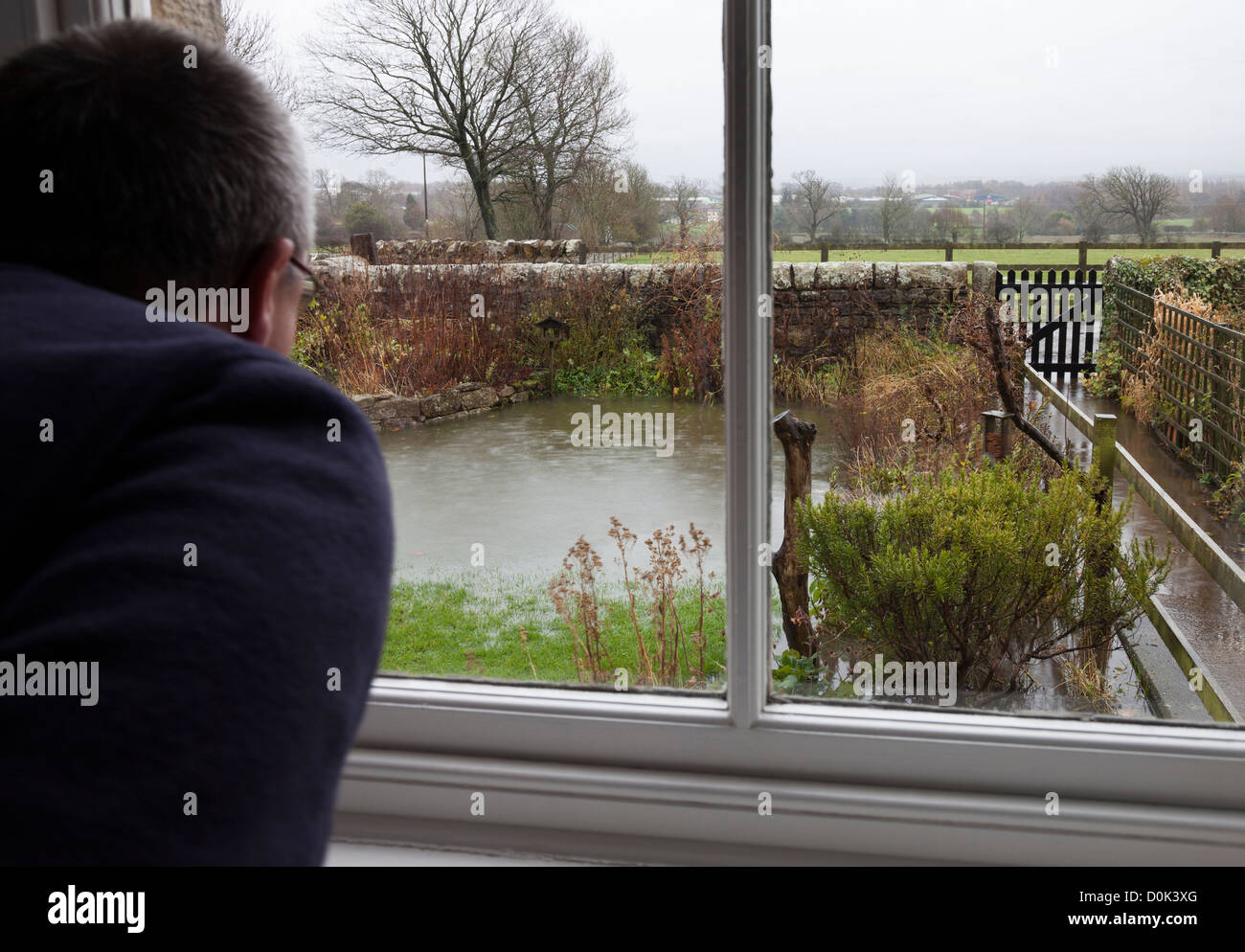 Concerned householder looking out of the window at rising flood water ...