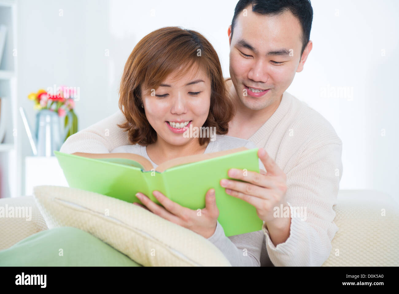 Beautiful loving Asian couple reading a book on the sofa Stock Photo ...