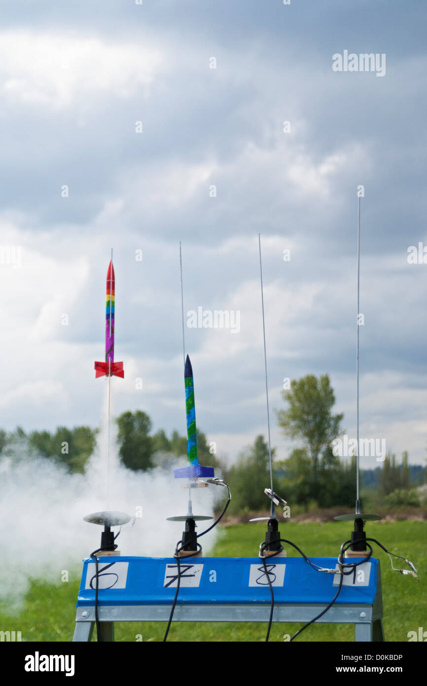 A row of brightly painted model rockets launch at a rocketry launch ...