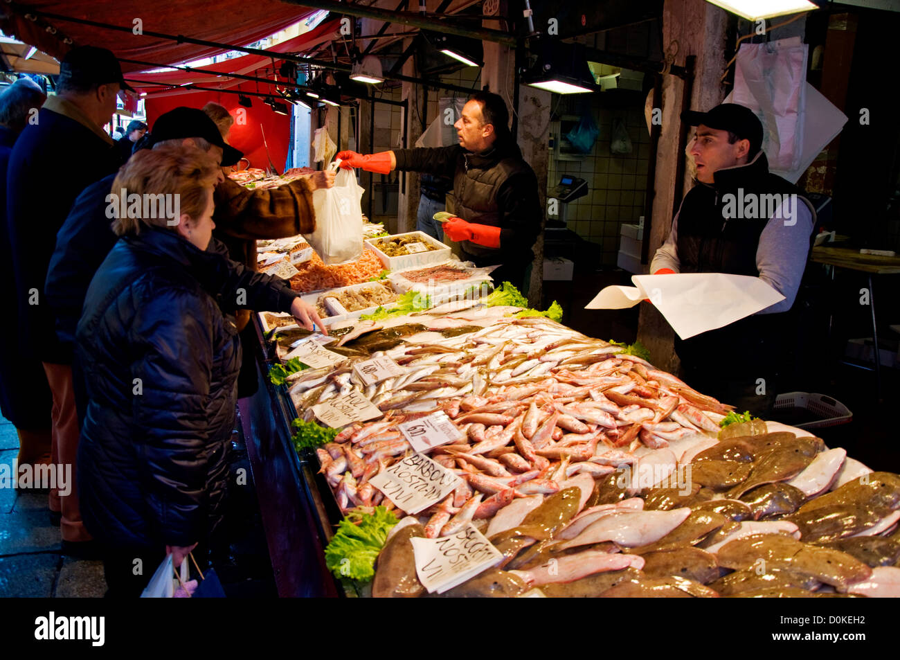 People buying fish from a market stall at the Fish Market in Venice ...