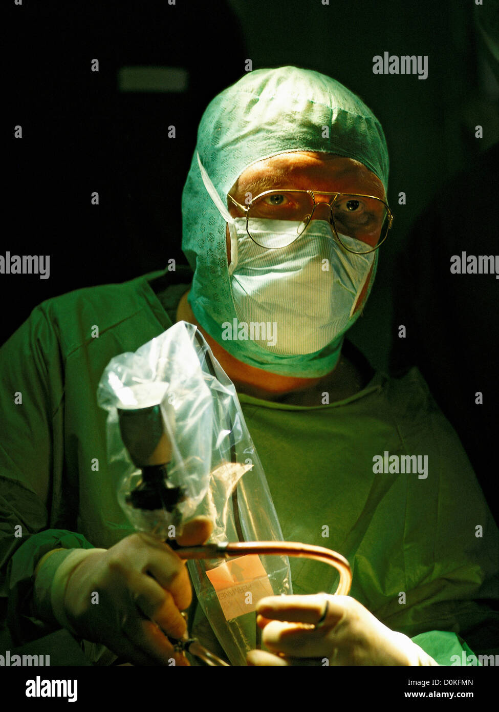 A masked surgeon uses an endoscope during a minimally invasive ...