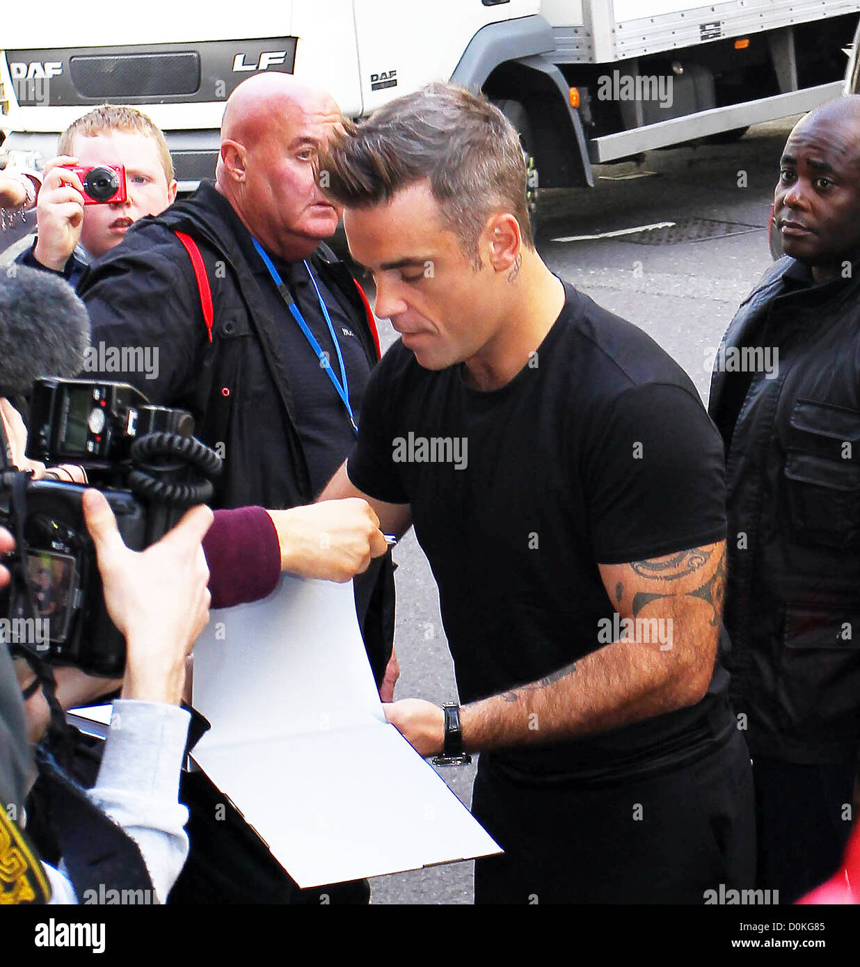 Robbie Williams signs autographs as he arrives at the BBC Radio One ...