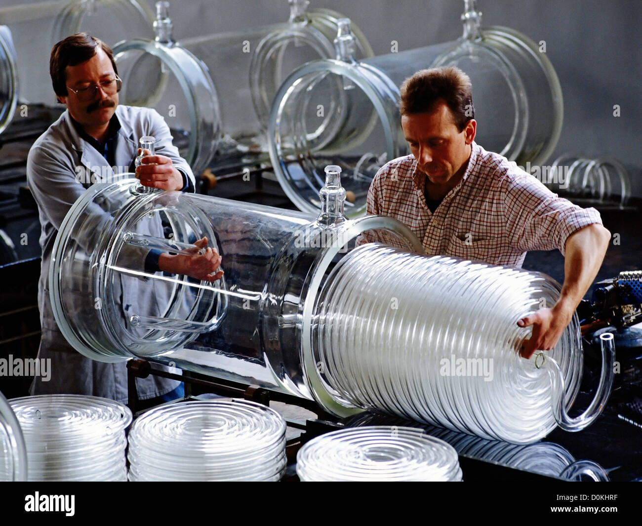 Workers constructing a large glass condenser for a chemical plant Stock ...