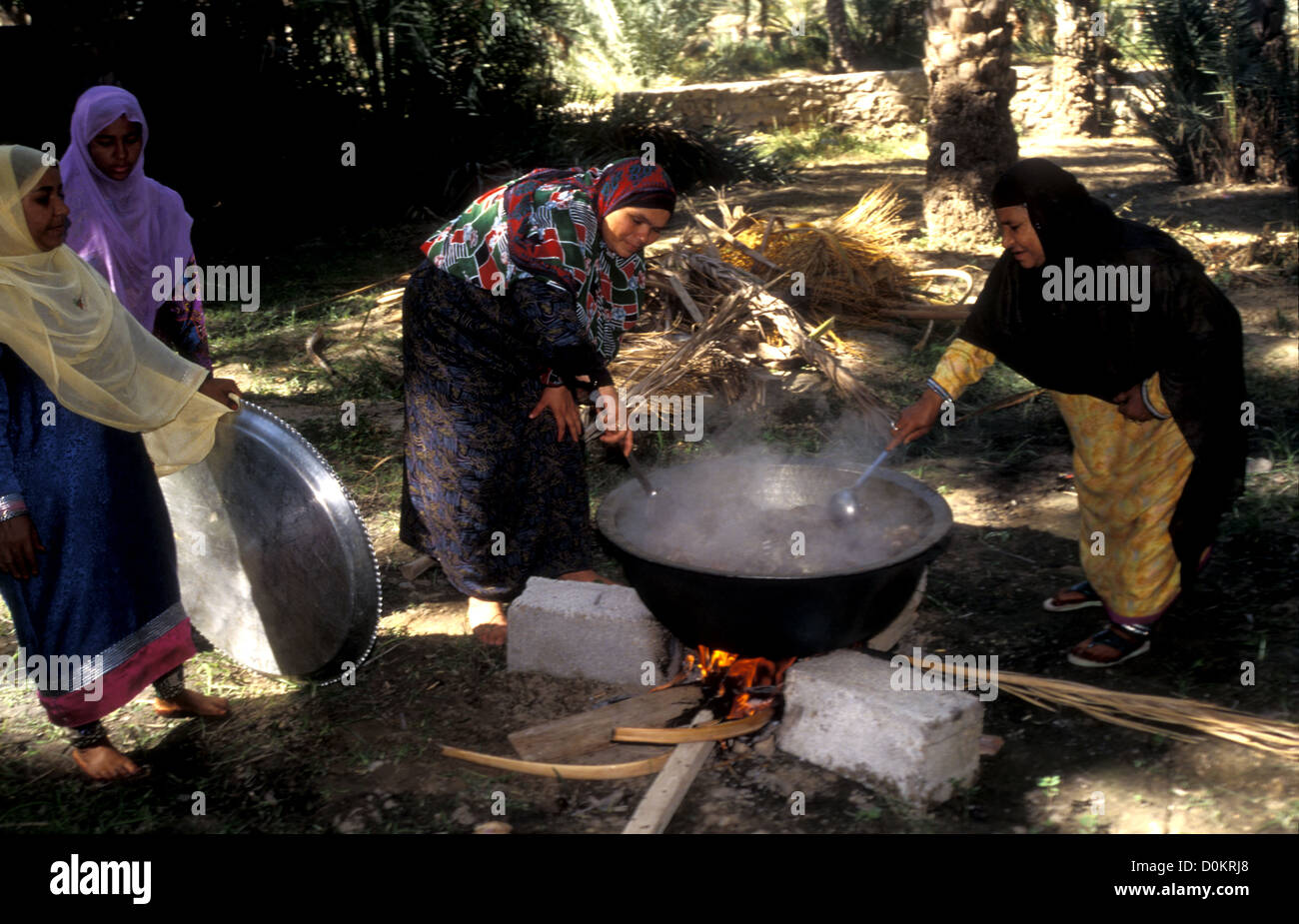 Village women cooking for a tribal wedding under the date palms ...