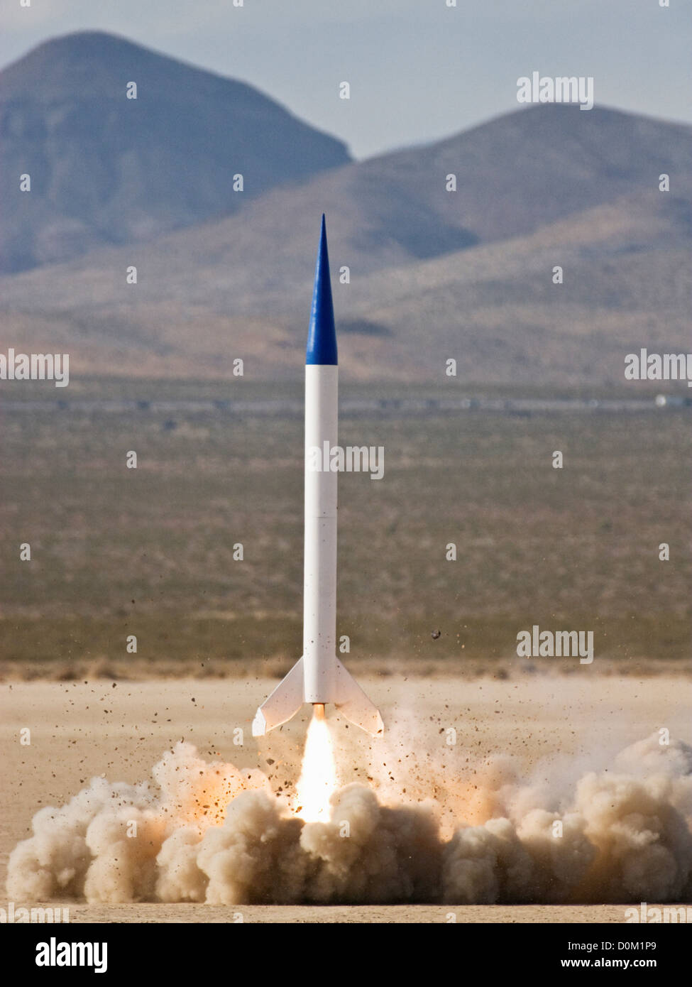 A blue and white rocket launches, blowing dirt off the floor of Jean ...