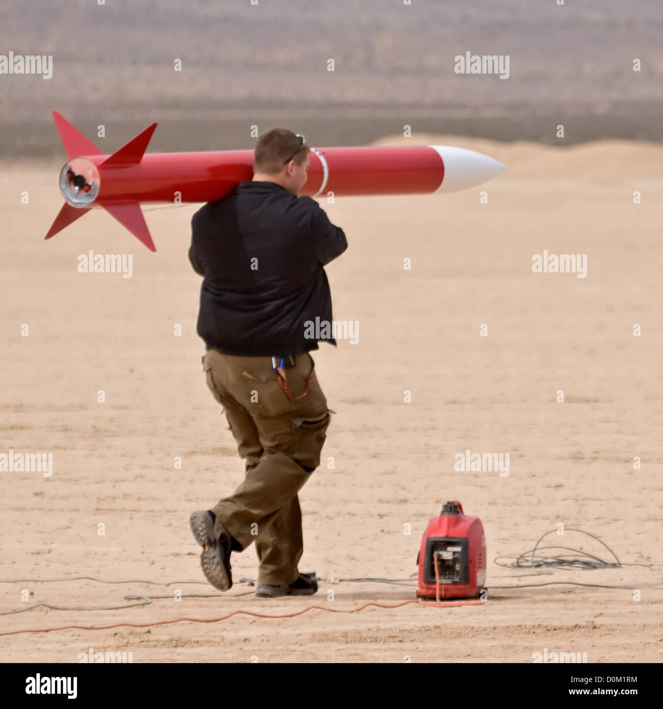 A young man carries one of Larry Foster's rockets out to a launch site ...