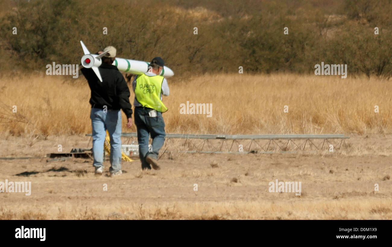 Larry Foster (in dark jacket) carries long green white rocket out ...
