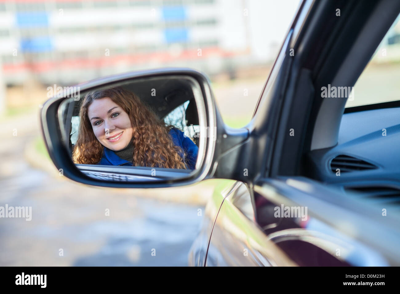 Beautiful woman looking in car back rear-view mirror sitting in vehicle ...