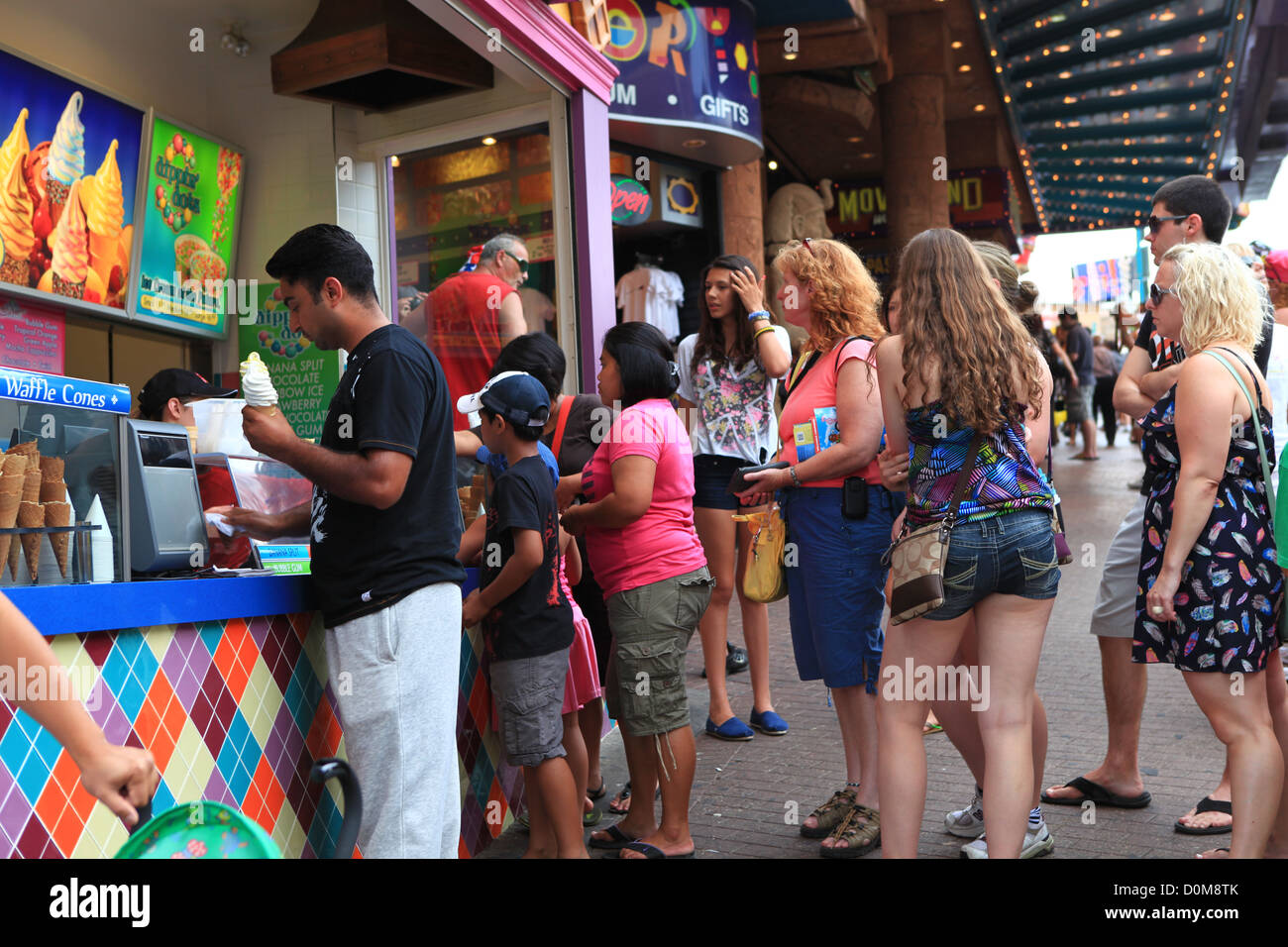 Long line of people waiting outside an ice cream store in summer heat ...
