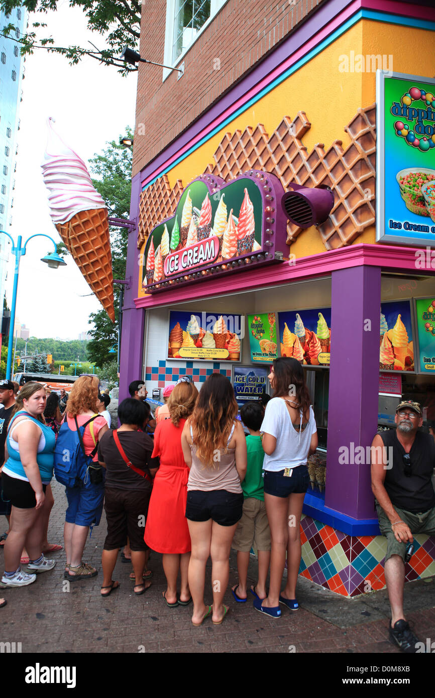 Long line of people waiting outside an ice cream store in summer heat ...