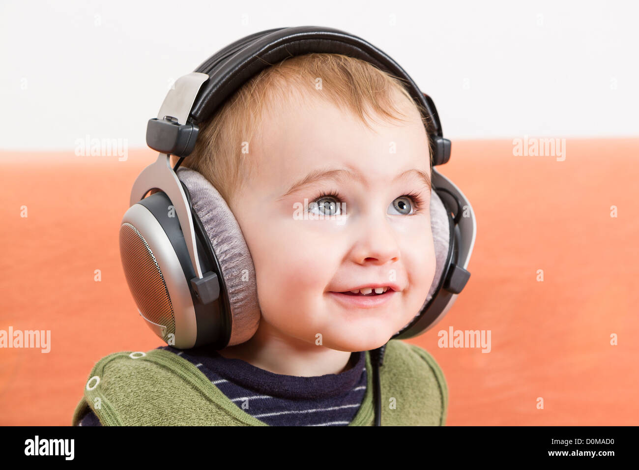young child on couch with big earphone Stock Photo - Alamy