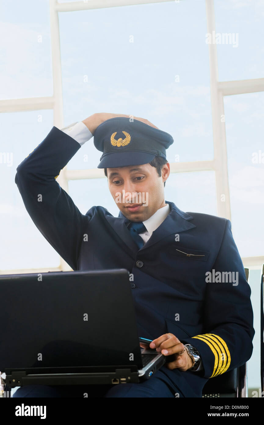 Pilot using a laptop at an airport and looking confused Stock Photo - Alamy