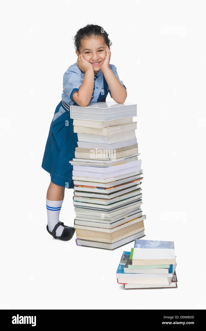 Schoolgirl leaning on a stack of books and smiling Stock Photo - Alamy