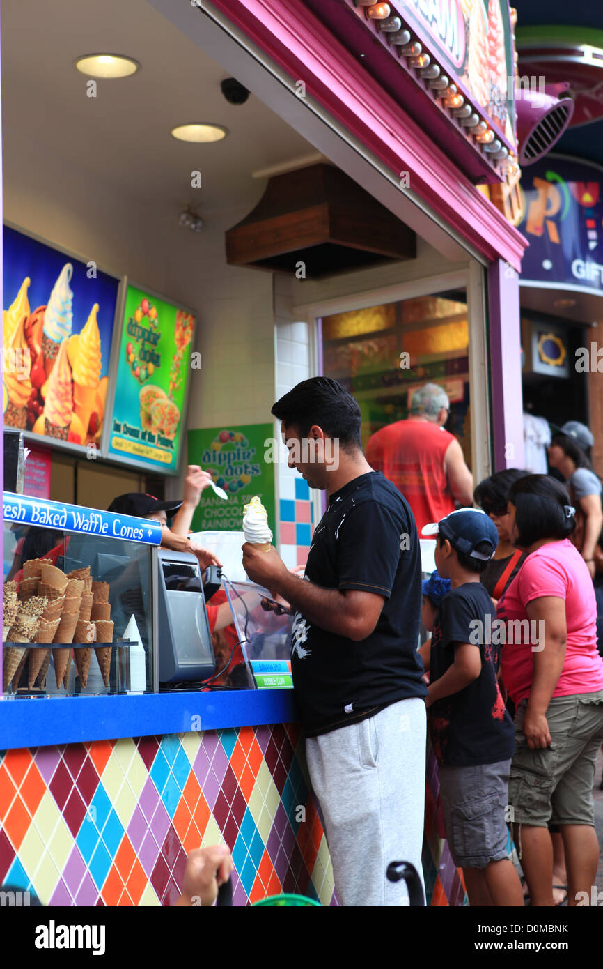 Long line of people waiting outside an ice cream store in summer heat ...