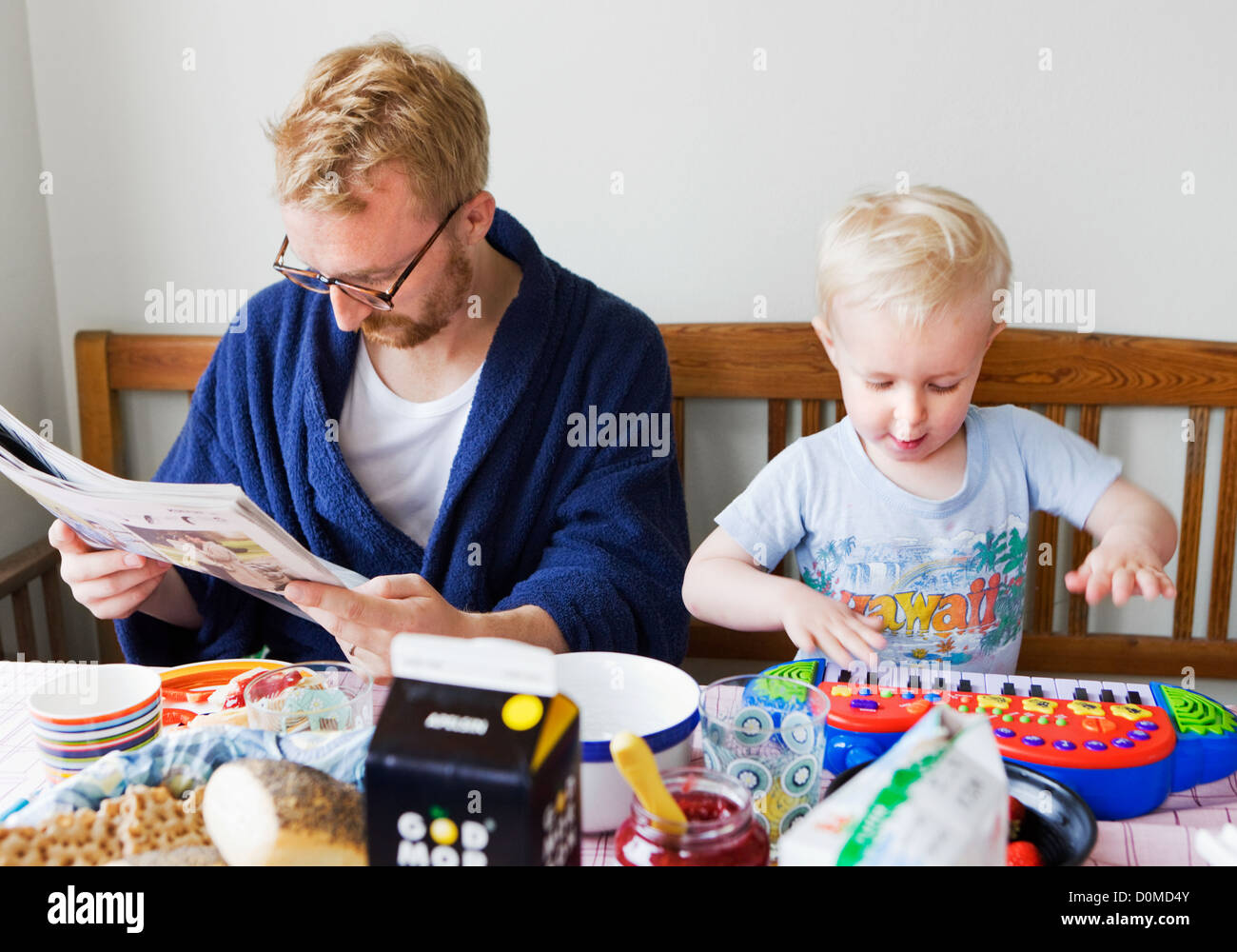 Father reading newspaper white son is playing Stock Photo - Alamy