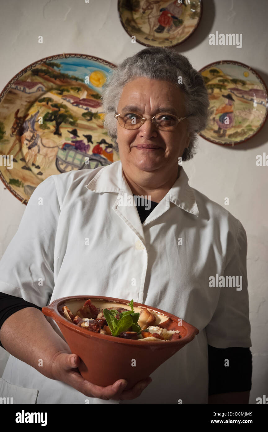 Portrait of a woman cook showing a bowl of traditional food, Alentejo ...