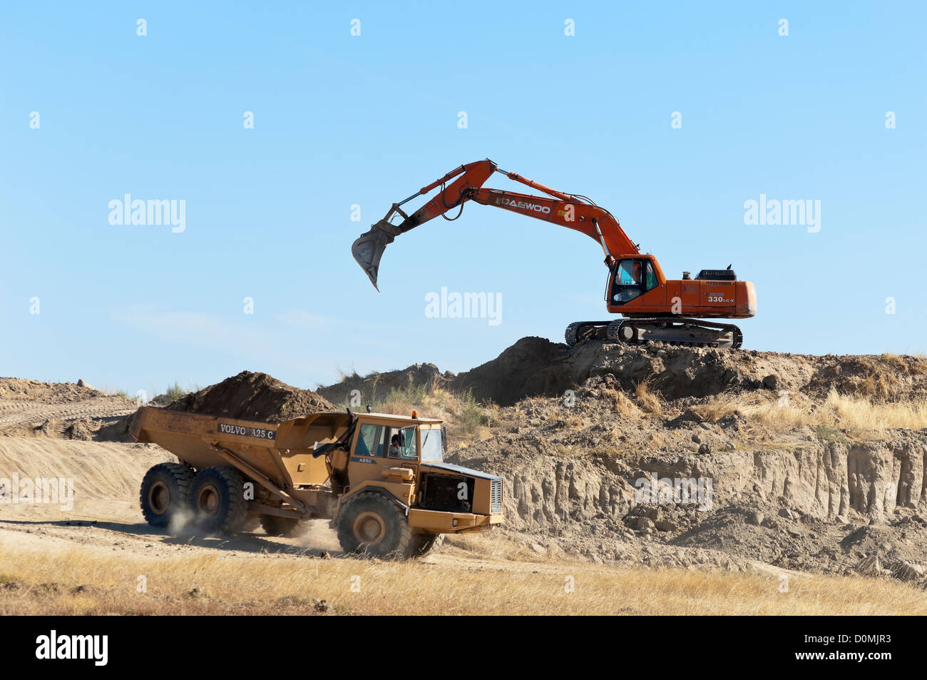 Daewoo excavator working in a construction site loading an articulated ...