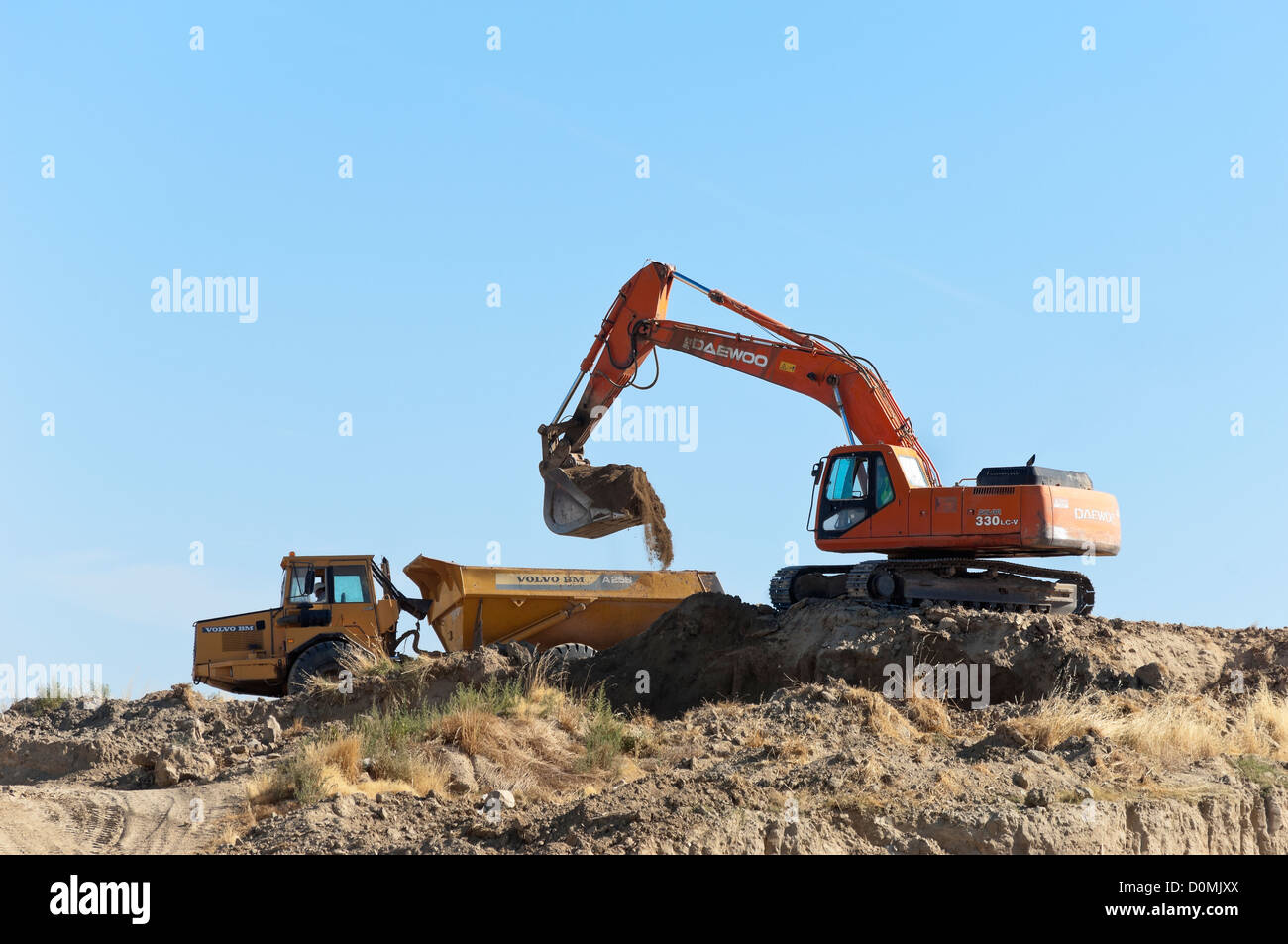 Daewoo excavator working in a construction site loading an articulated ...