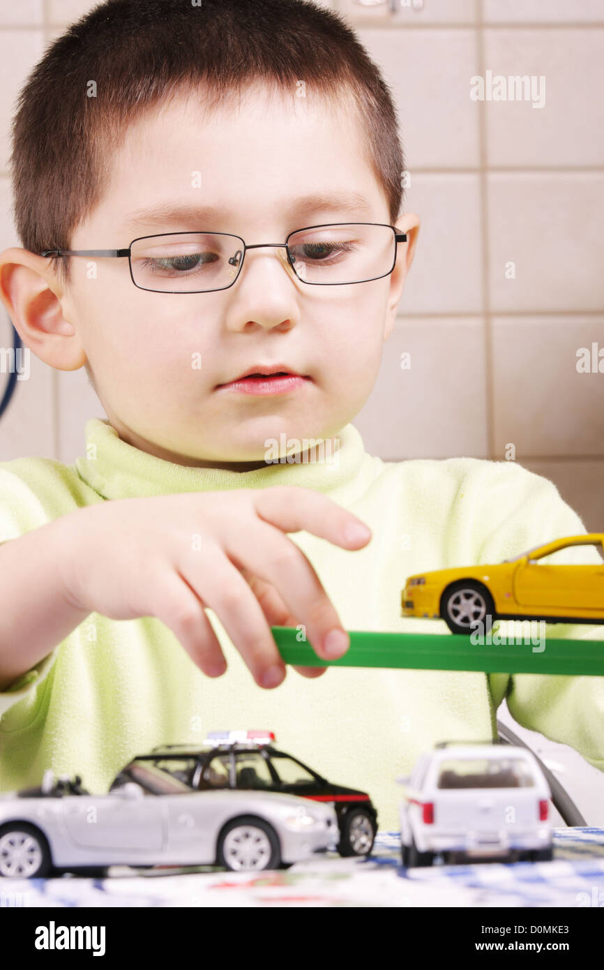 Boy in green playing with cars Stock Photo - Alamy