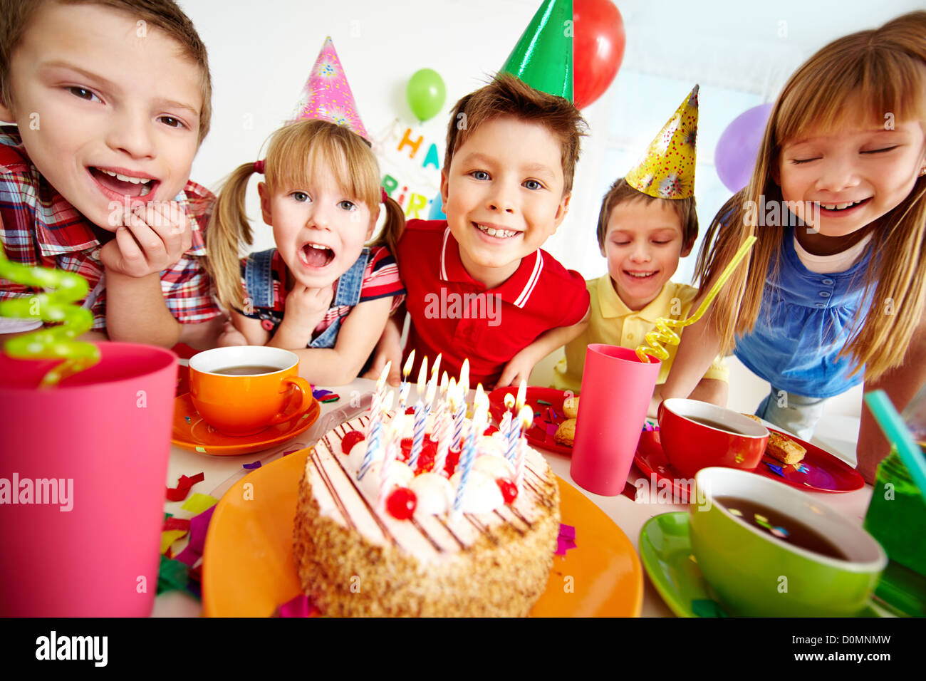 Group of adorable kids gathered around birthday cake with candles Stock ...