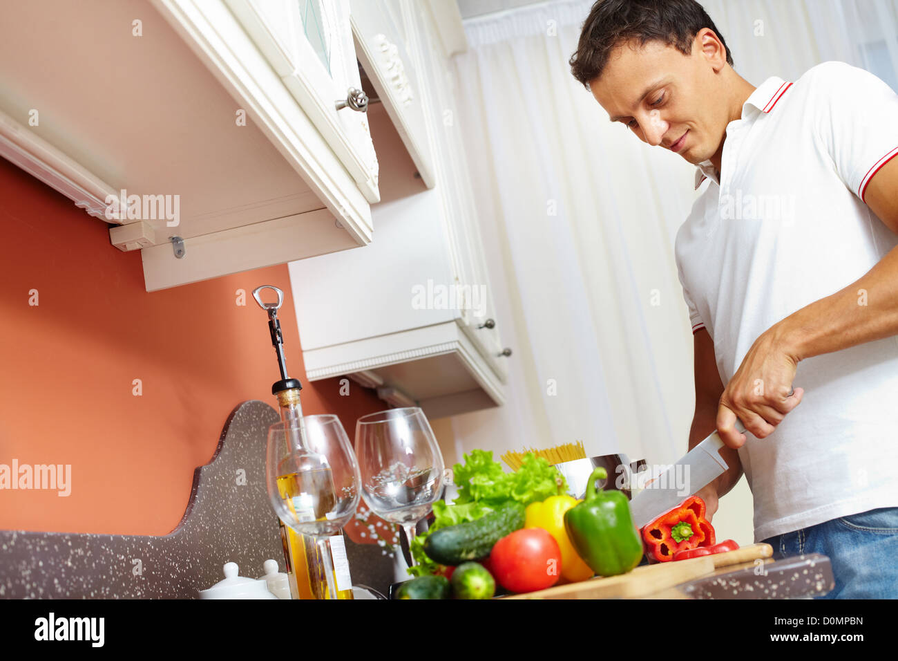 Portrait of young man cutting vegetables in the kitchen Stock Photo - Alamy