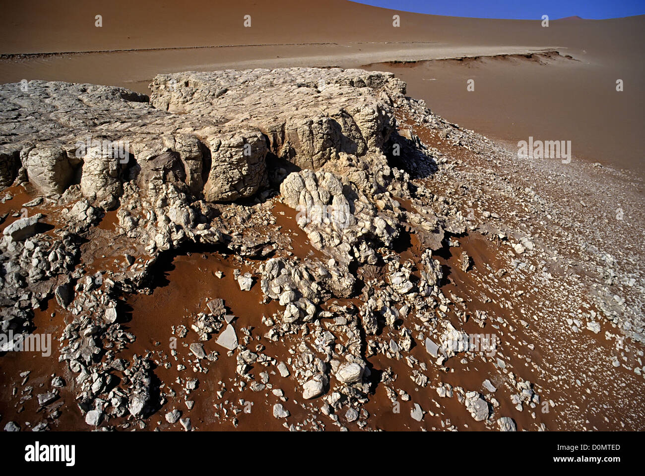 Dry baked clay emerging from beneath sand dunes in vlei, Namib desert ...
