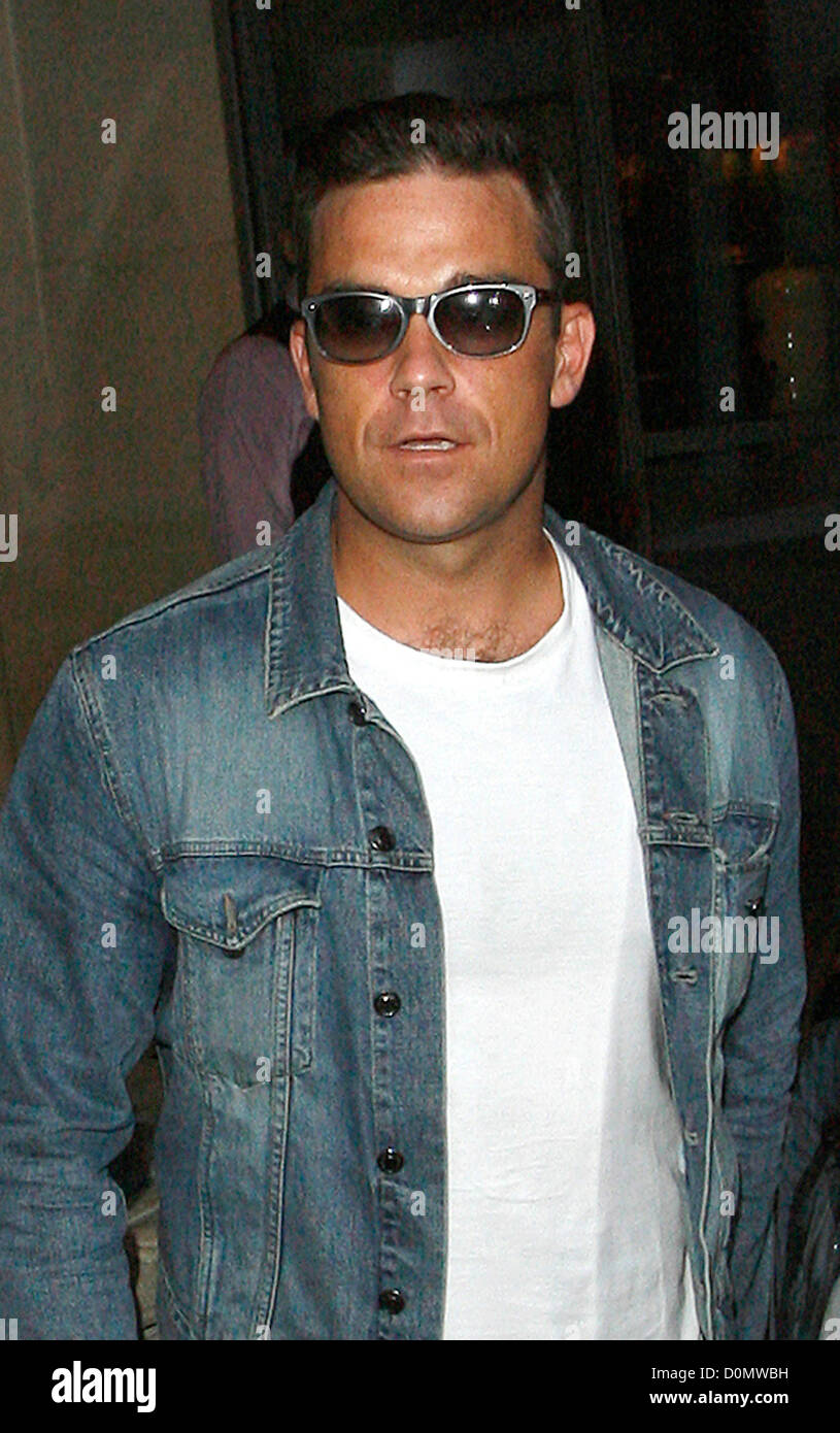 Robbie Williams wearing a denim jacket and jeans leaves his hotel ...