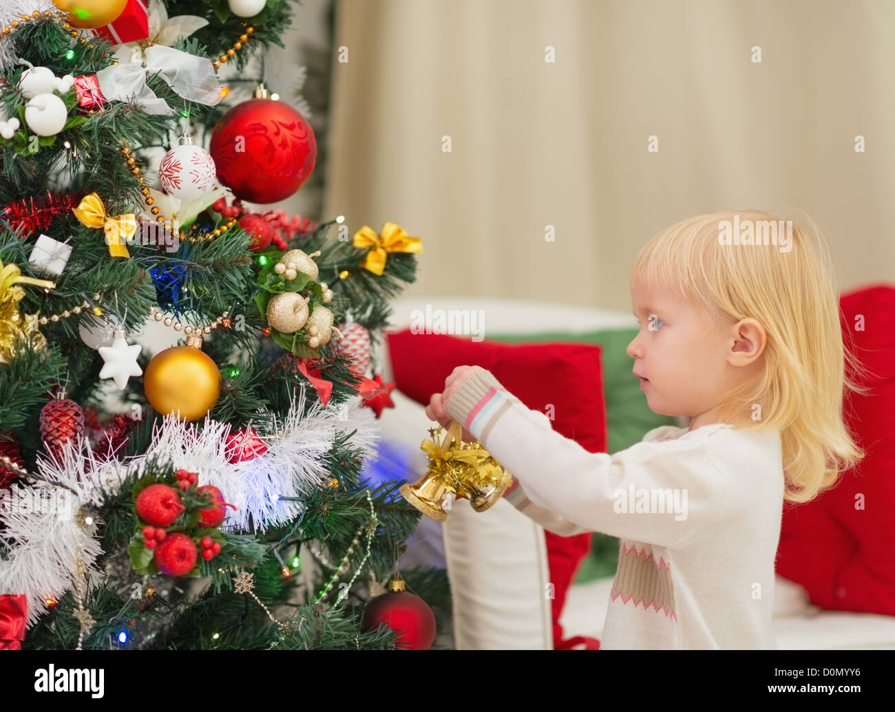 Baby decorating Christmas tree Stock Photo - Alamy