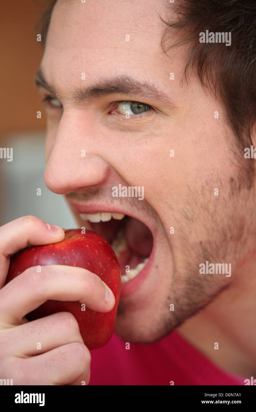 Man biting into a red apple Stock Photo - Alamy