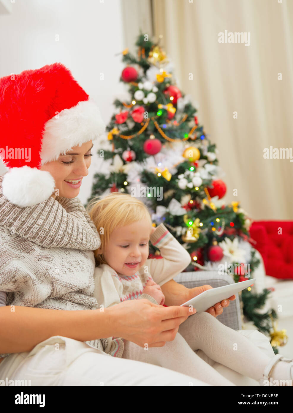 Happy mother and kid using tablet PC near Christmas tree Stock Photo ...