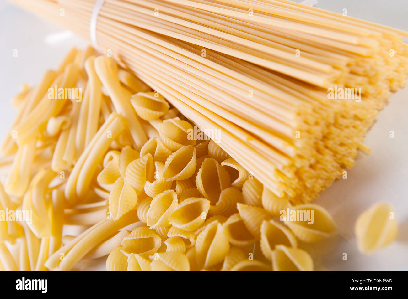 A bunch of spaghetti and shells pasta over light background Stock Photo ...
