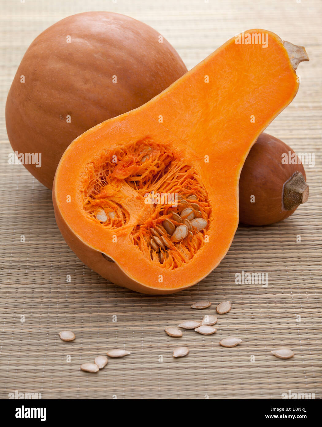 Ripe orange gourds and half with white seeds on rural straw woven ...