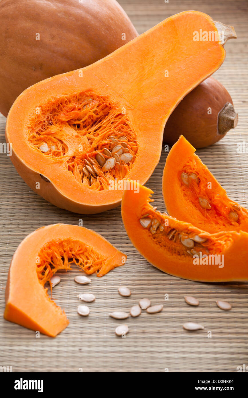 Ripe orange gourds and half, sliced fleshy segments and white seeds on ...