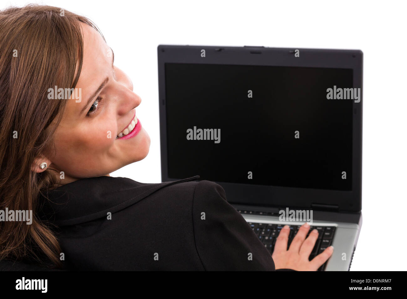 Businesswoman working on laptop and looking back over her shoulder ...