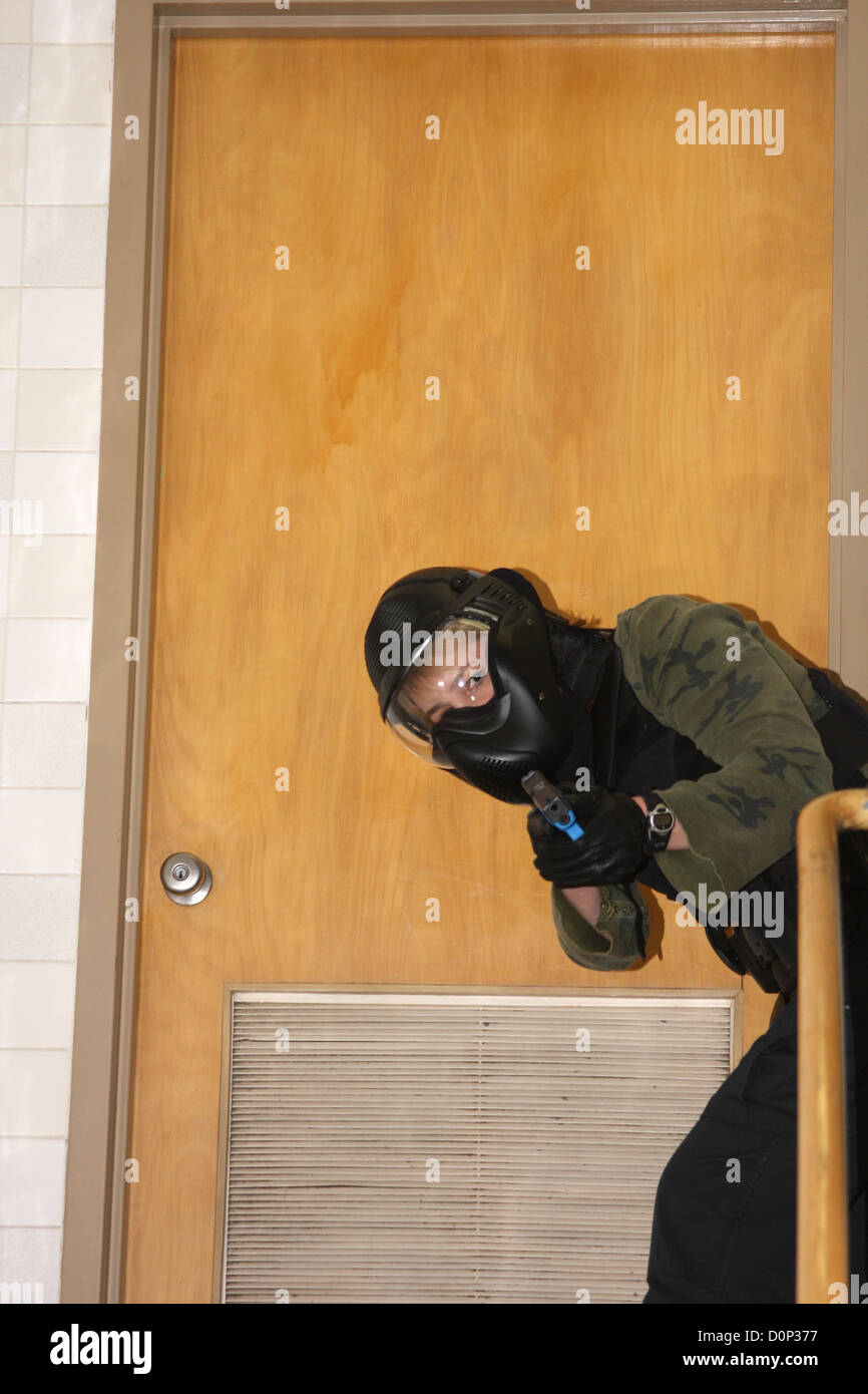 A woman police officer in training holding a paint ball simulated gun ...