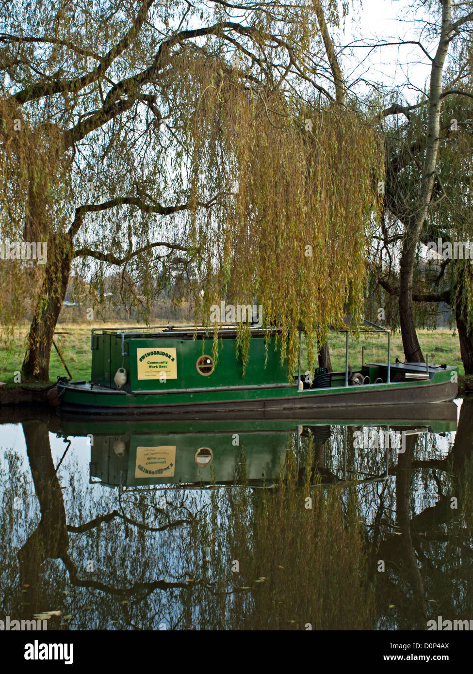 Canal boat reflected on the River Wey, a tributary of the River Thames ...