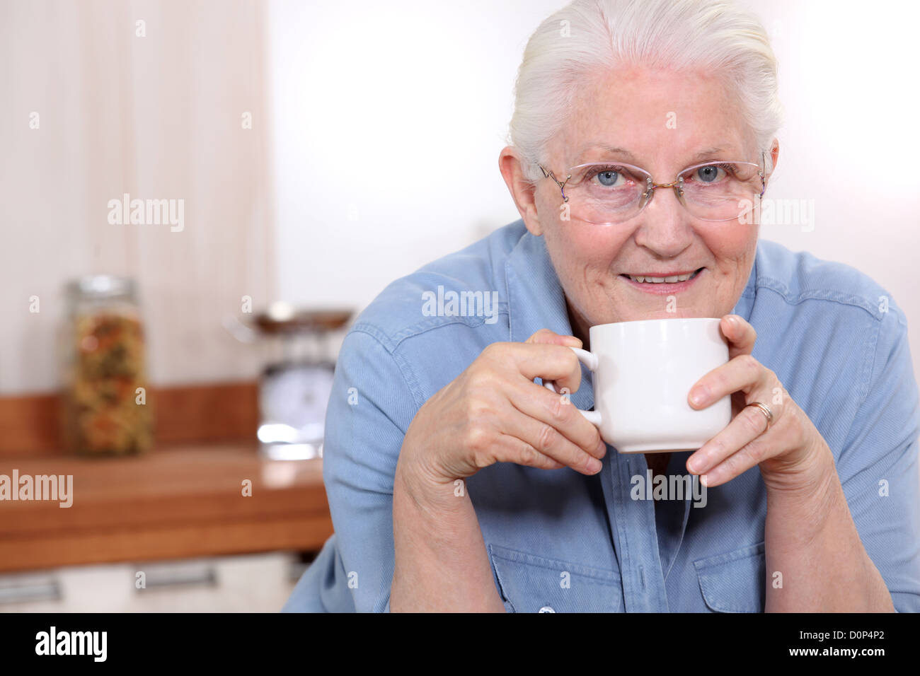 Elderly lady enjoying cup of tea in her kitchen Stock Photo - Alamy