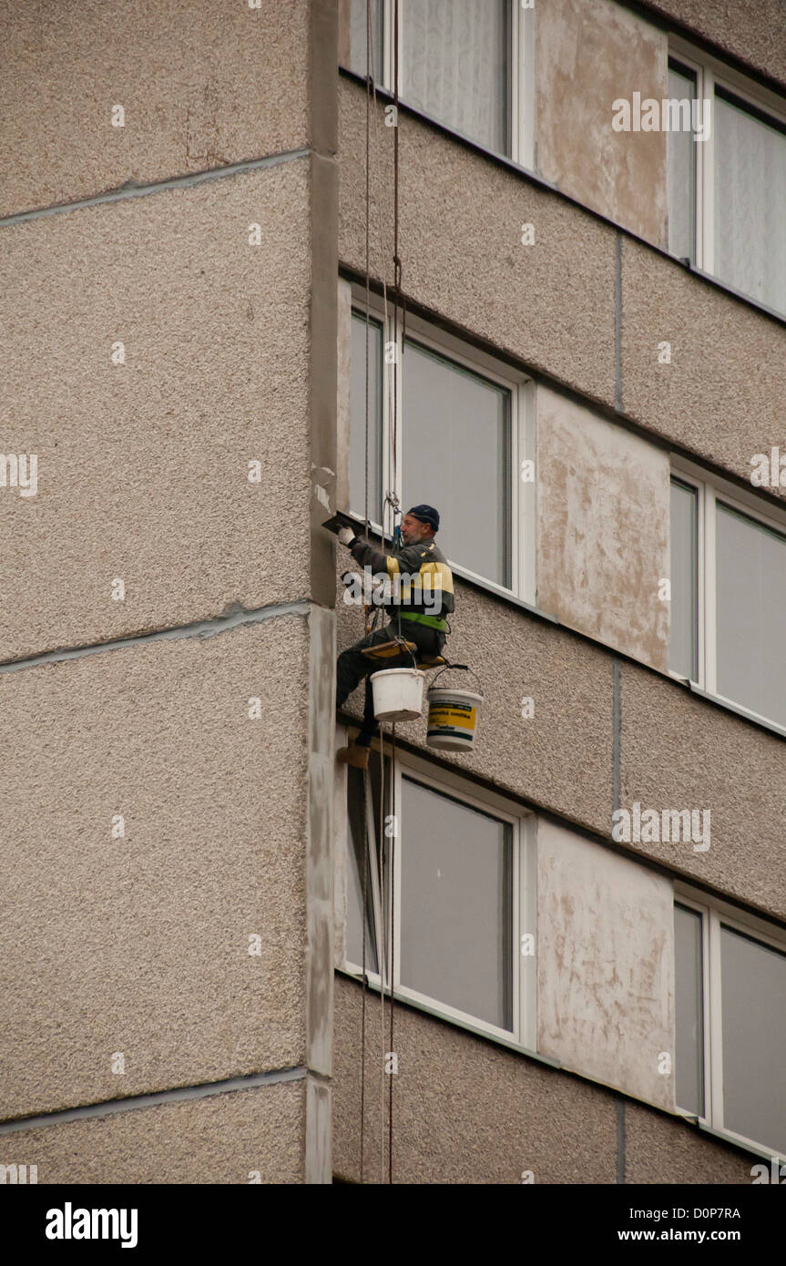man hanging on ropes and repairing the exterior of a multi-story ...