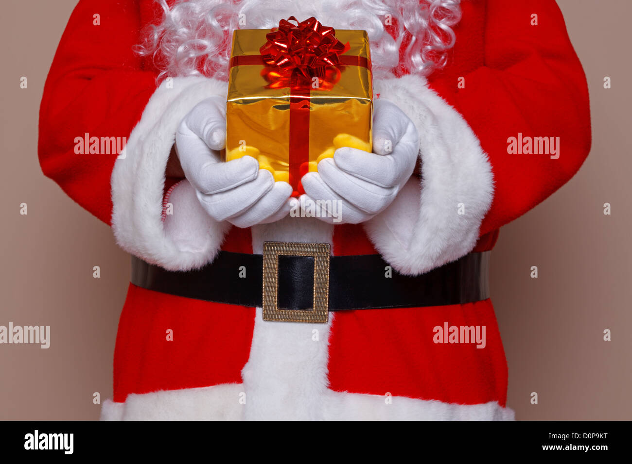 Santa Claus holding a gift wrapped present with gold wrapping paper and ...