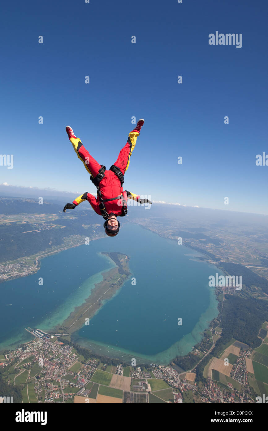 Skydiver girl is flying in a head-down position over a beautiful lake ...