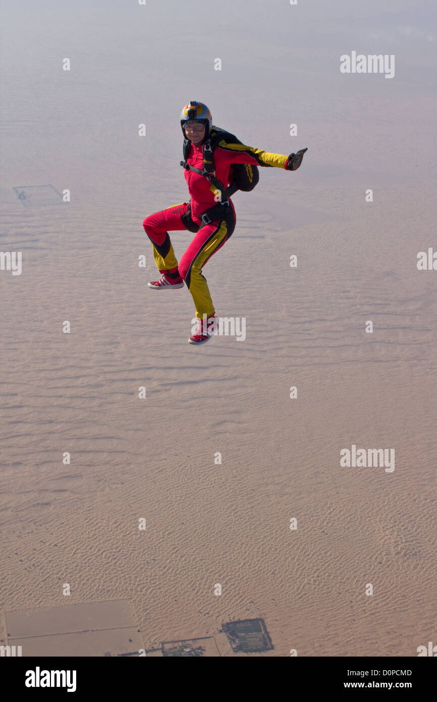Skydiver girl in a sit-up position is falling free through the blue sky ...