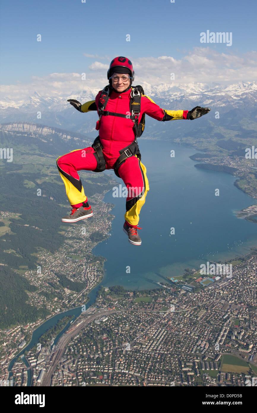 This skydiver woman is falling free in a sit position over a big city ...