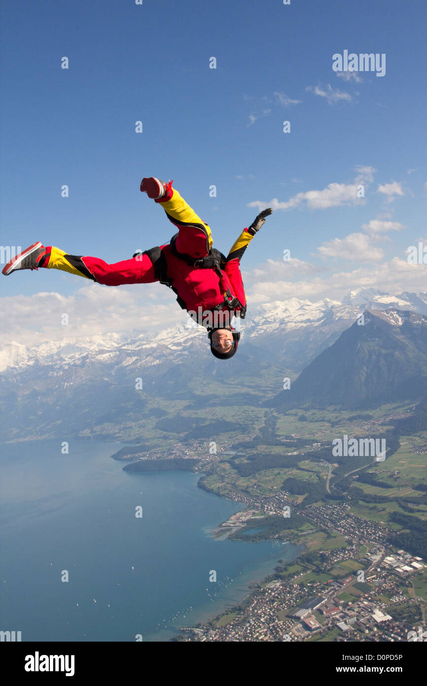 Skydiver girl is flying head low over a beautiful lake. She tries to do ...