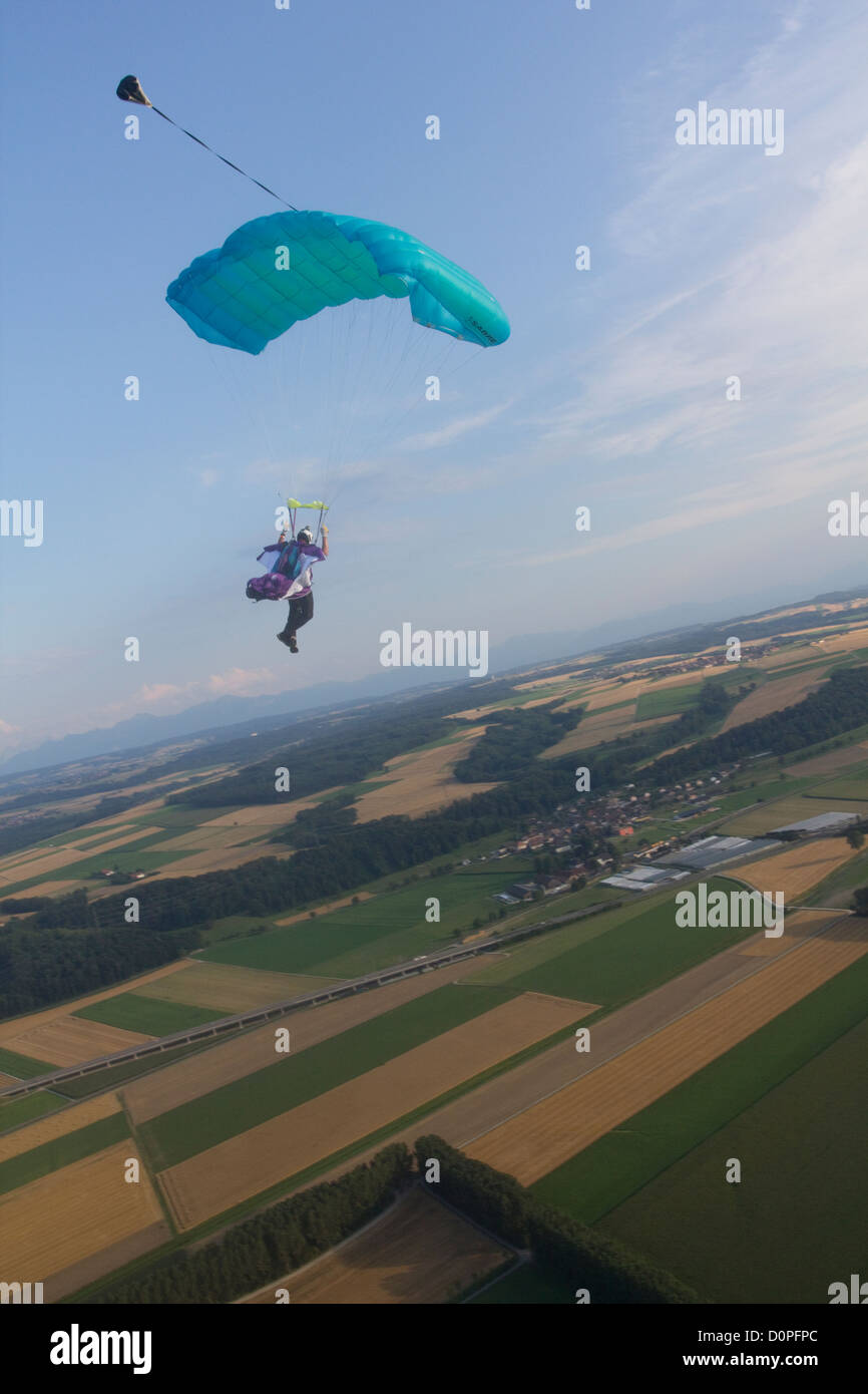 Skydiver under canopy is flying over big forest and is looking out for ...