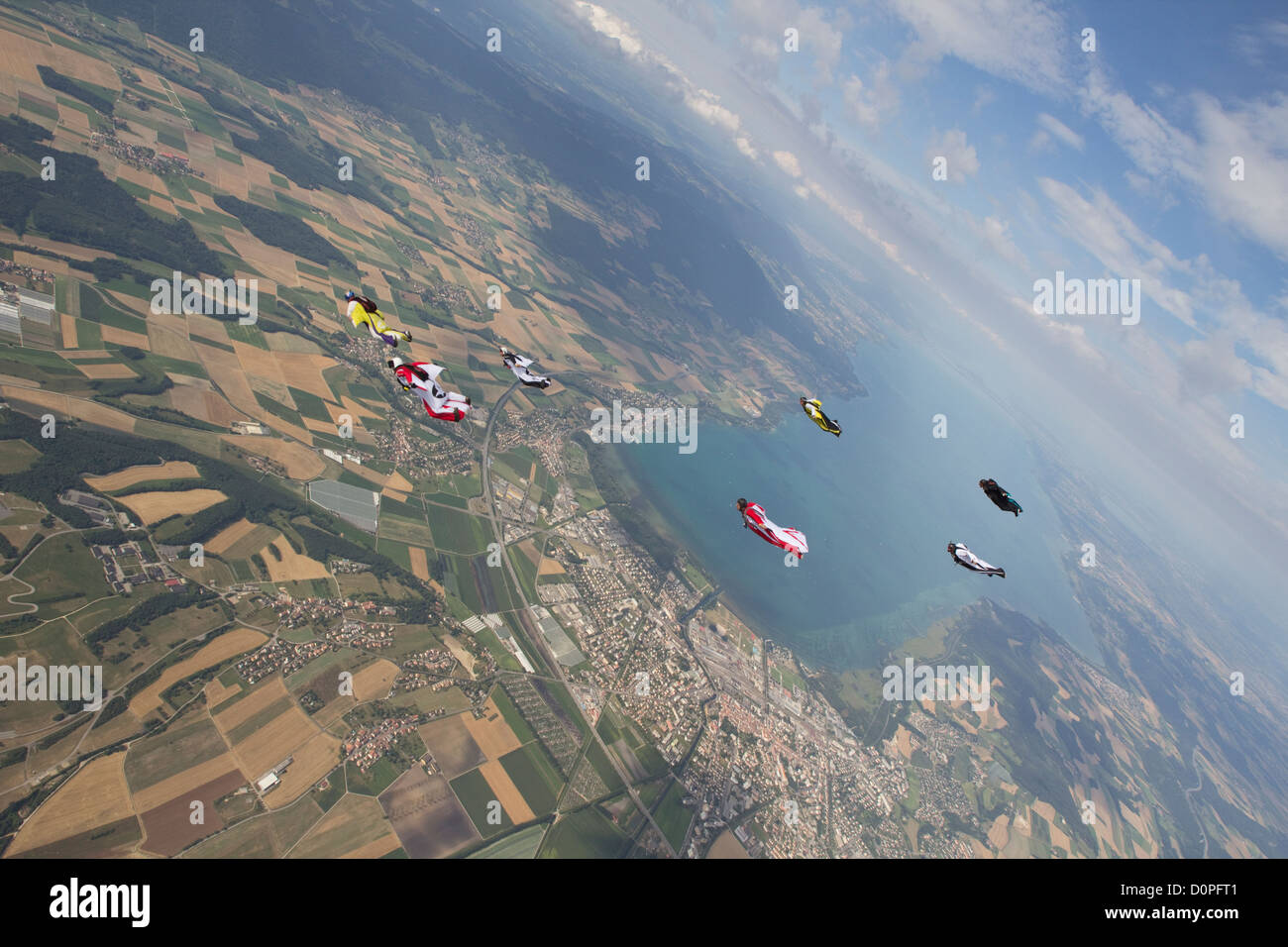 Wingsuit skydivers are flying together in an arrow formation over ...