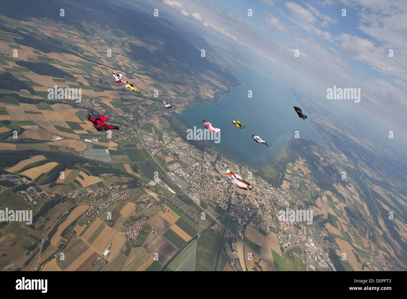 Wingsuit skydivers are flying together in an arrow formation over ...