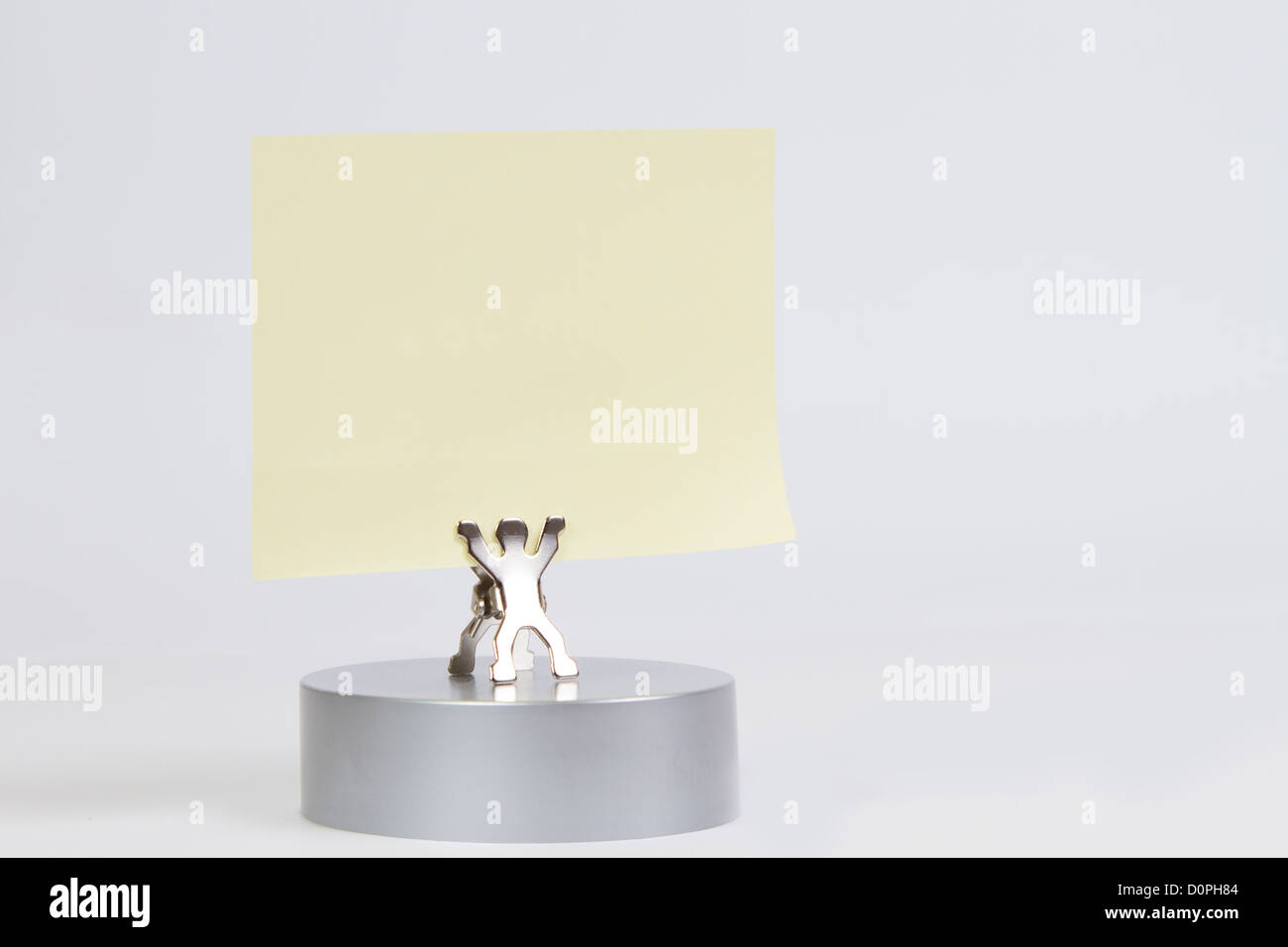 Yellow post-it on a metal support against white background Stock Photo ...