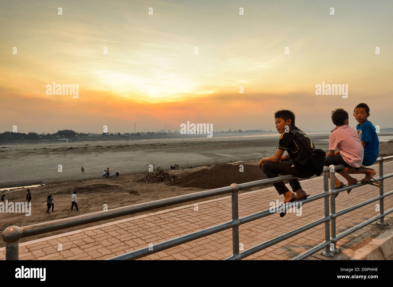 VIENTIANE, Laos - Three boys sit on the railing of a walkway along the ...
