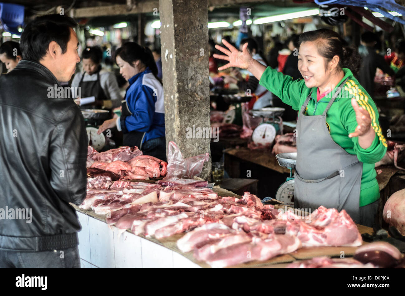 A butcher talks with a customer at the large and bustling morning ...